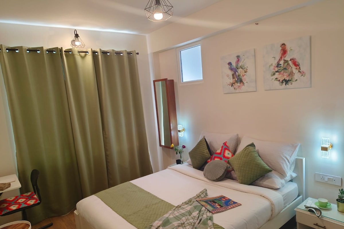 Quarto de hotel com cama, cadeira, mesa de cabeceira e janela.