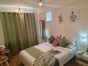 Quarto de hotel com cama, cadeira, mesa de cabeceira e janela.