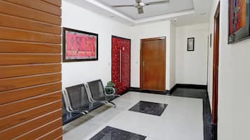 Um corredor com ventilador de teto, uma porta de madeira, uma porta vermelha e um banco.