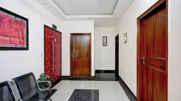 Um corredor com uma mesa de recepção, uma porta vermelha e uma porta de madeira.