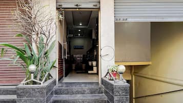 Uma escadaria leva a um quarto com vista para a cidade, uma porta com maçaneta e um vaso de planta no patamar.