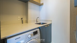Uma cozinha compacta com máquina de lavar embutida, pia e armários de madeira.