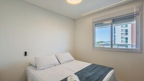 Quarto de hotel com uma cama, uma janela e vista para edifícios.
