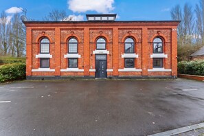 Um edifício de tijolos vermelhos com janelas em arco e uma porta preta, com a inscrição '1898 Pump House'.