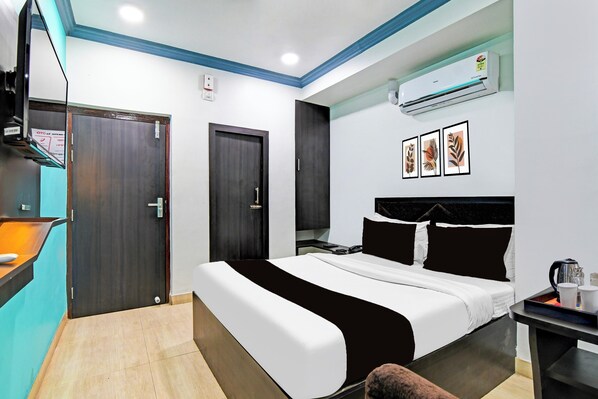Quarto de hotel com cama, mesa de cabeceira, ar condicionado e televisão fixada na parede.