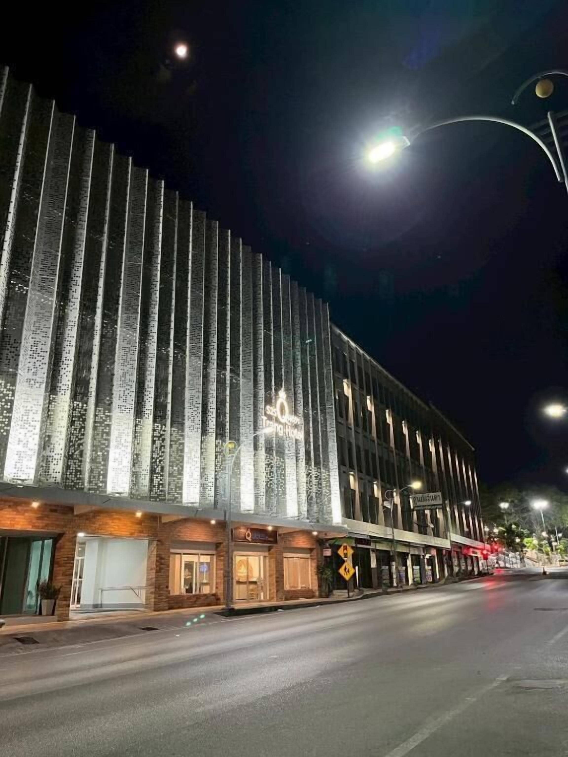 A modern building with a reflective facade, a ground-level entrance, and a street view at night.