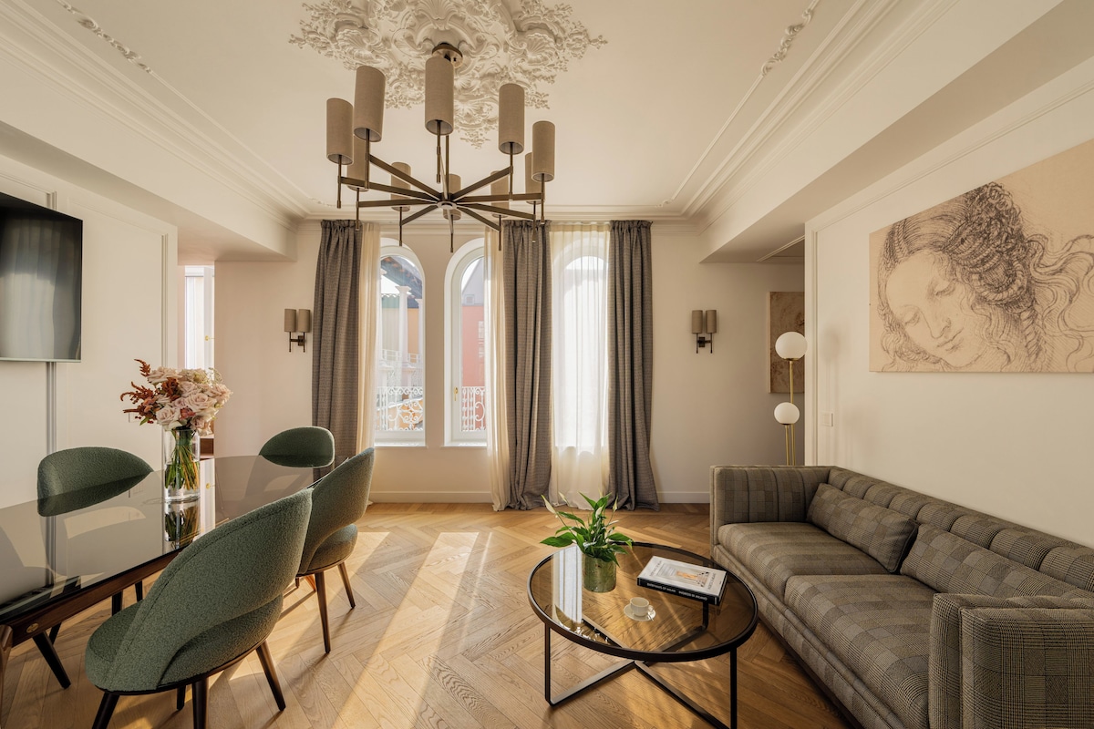 Uma sala de estar moderna com sofá, cadeiras, mesa de centro e lustre.