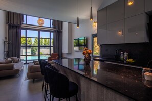 Cozinha moderna com uma ilha grande, banquetas e área de refeições com sofá e cadeiras.