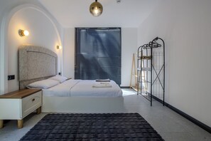 Quarto moderno com cama, mesa de cabeceira e luminária suspensa.