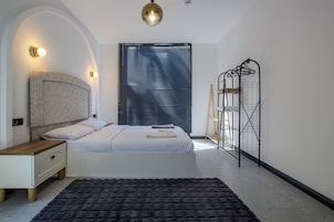 Quarto moderno com cama, mesa de cabeceira e luminária suspensa.