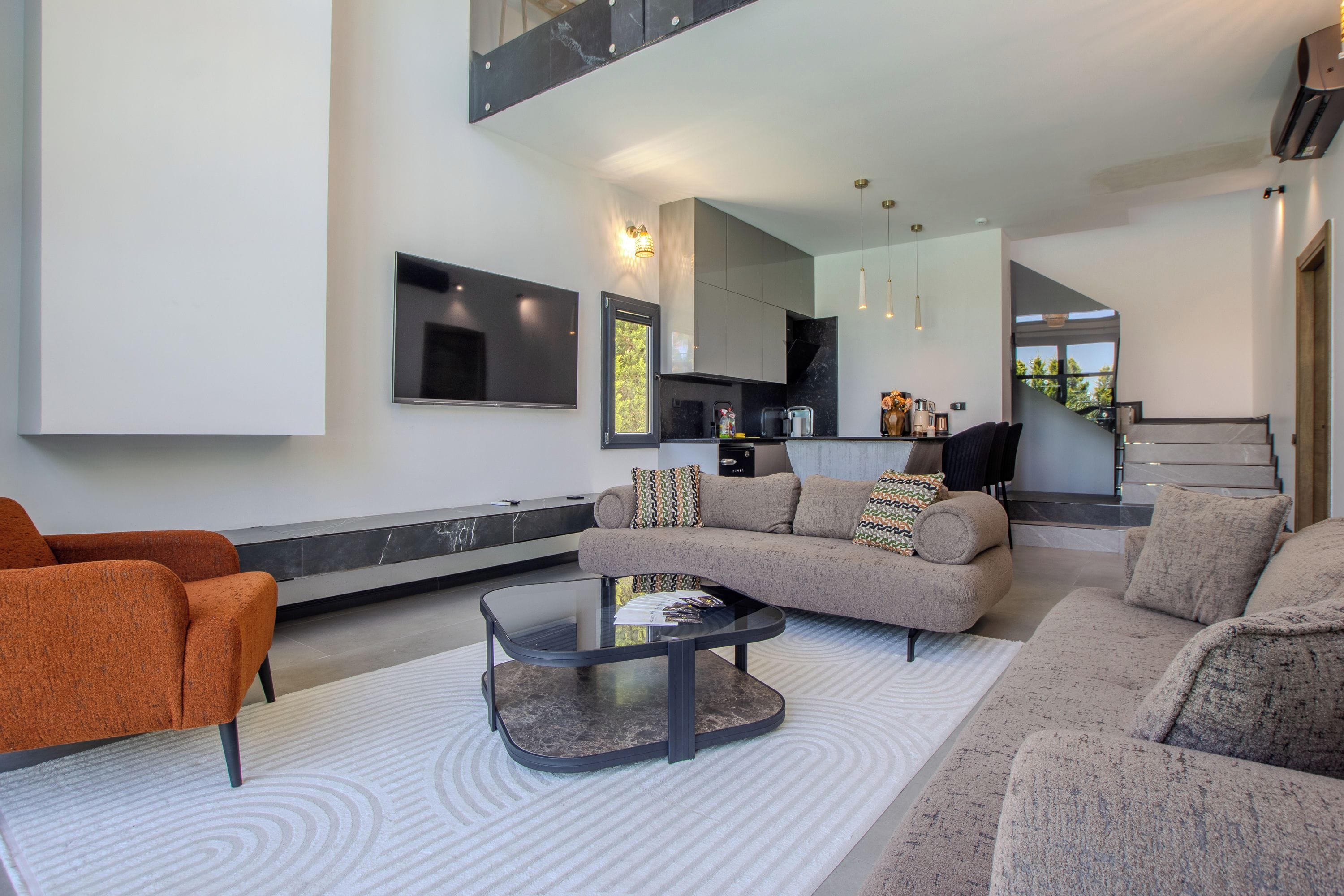 Uma sala de estar moderna com um sofá modular, uma mesa de centro e uma TV de tela plana fixada na parede.