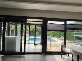 Um interior moderno com grandes portas de correr de vidro que dão para uma área de piscina ao ar livre.