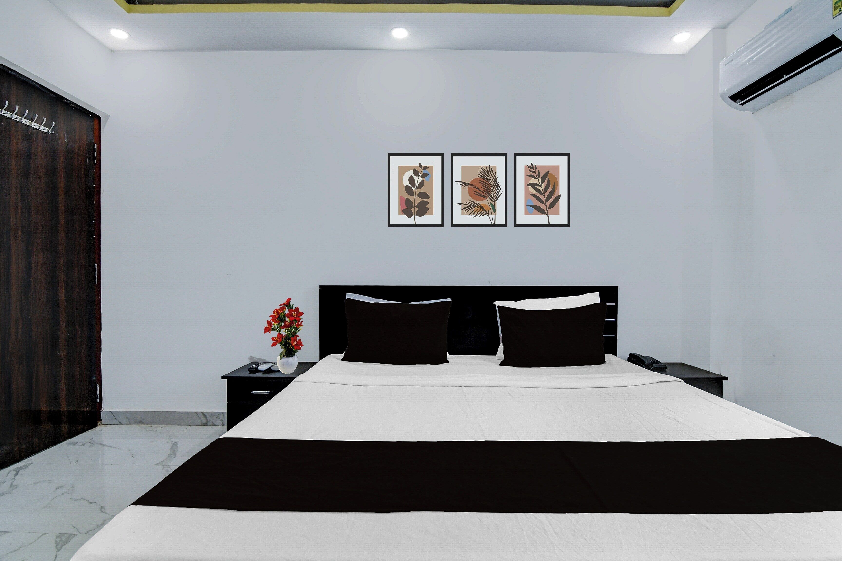 Quarto com cama, mesas de cabeceira, ar condicionado fixado na parede e quadros decorativos.