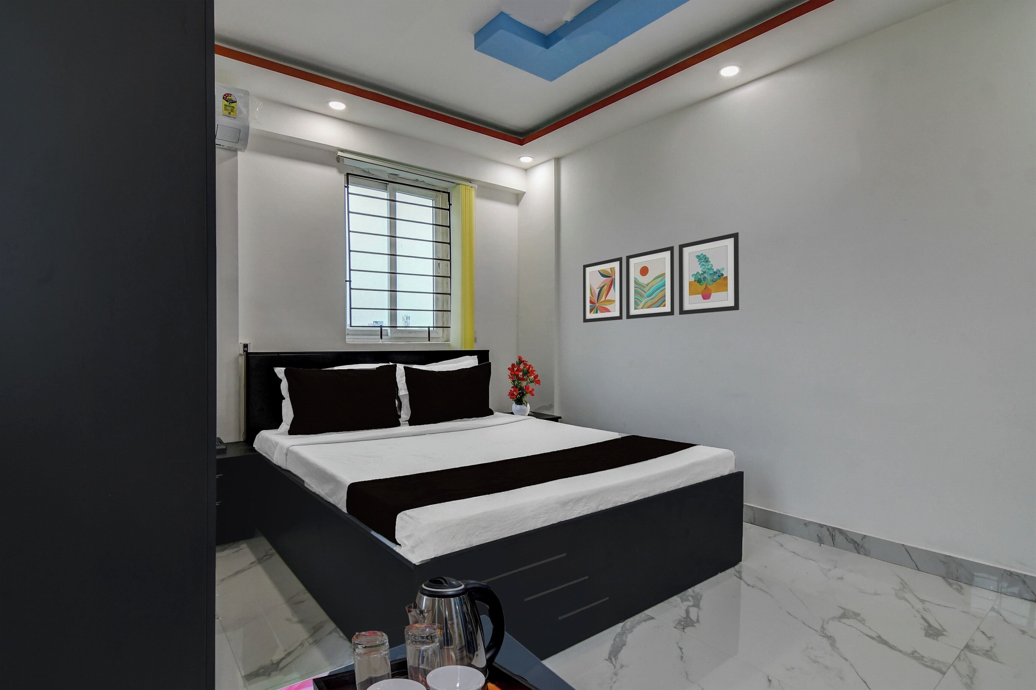Um quarto moderno com uma cama, uma janela, ar condicionado fixado na parede e obras de arte emolduradas.