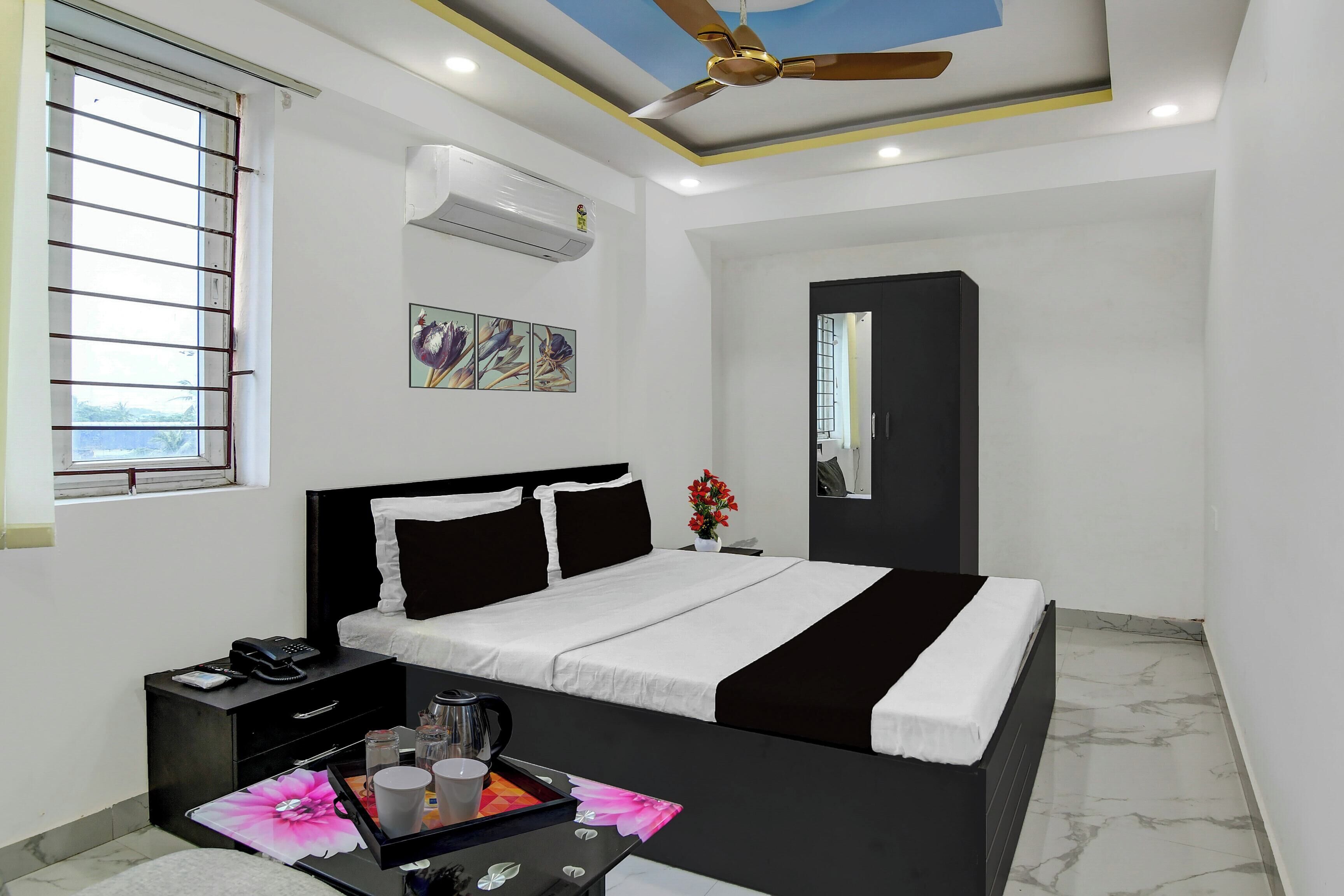 Quarto moderno com cama, mesa de cabeceira e ventoinha no teto.