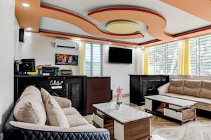 Uma sala de estar moderna com um sofá, uma mesa de centro e uma televisão de tela plana na parede.