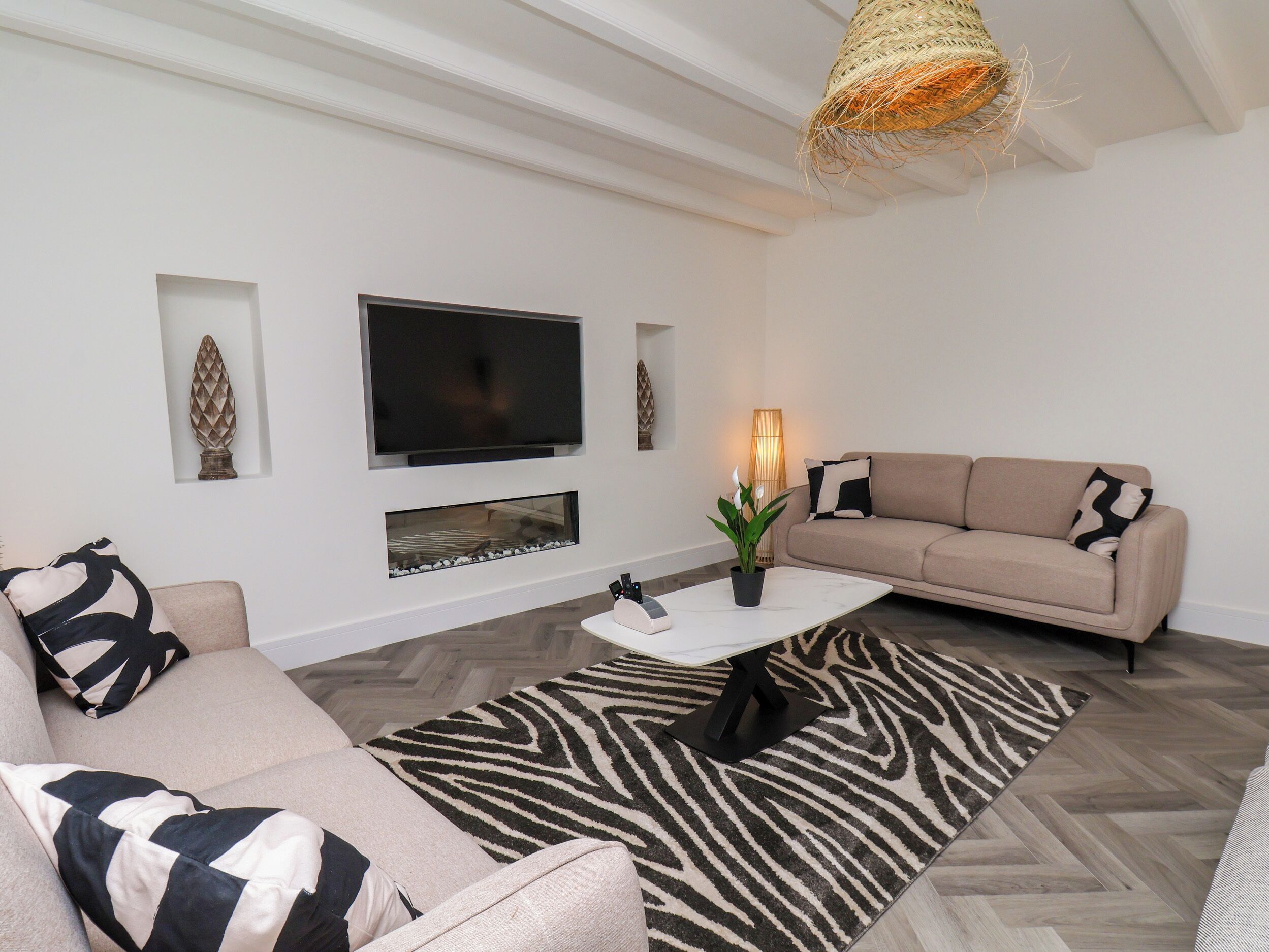 Uma sala de estar moderna com um sofá, uma mesa de centro, uma TV e objetos decorativos.