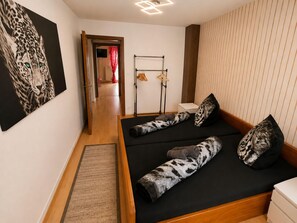 Quarto moderno com uma cama, um quadro, piso de madeira e um corredor que leva a outro quarto.
