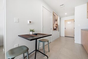 Um interior moderno com uma mesa de jantar, duas cadeiras, um vaso de planta e uma grande pintura abstrata na parede.