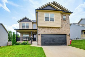 A two-story residential building with a front garage, a covered porch, and a brick facade.