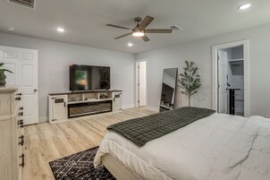 Quarto com uma cama, televisão, ventoinha no teto e guarda-roupa.