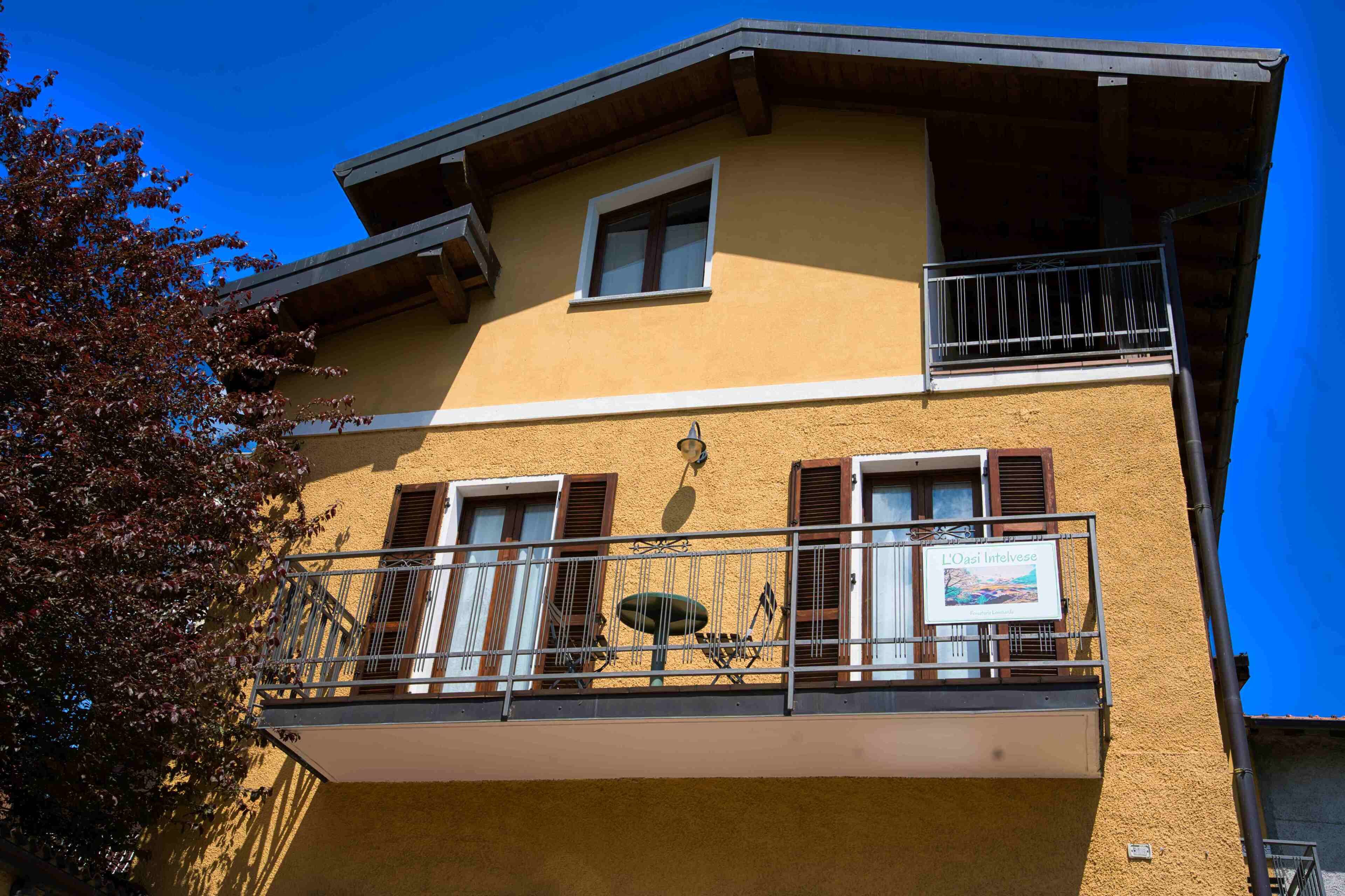 Um edifício de dois andares com uma varanda, uma janela e uma placa.