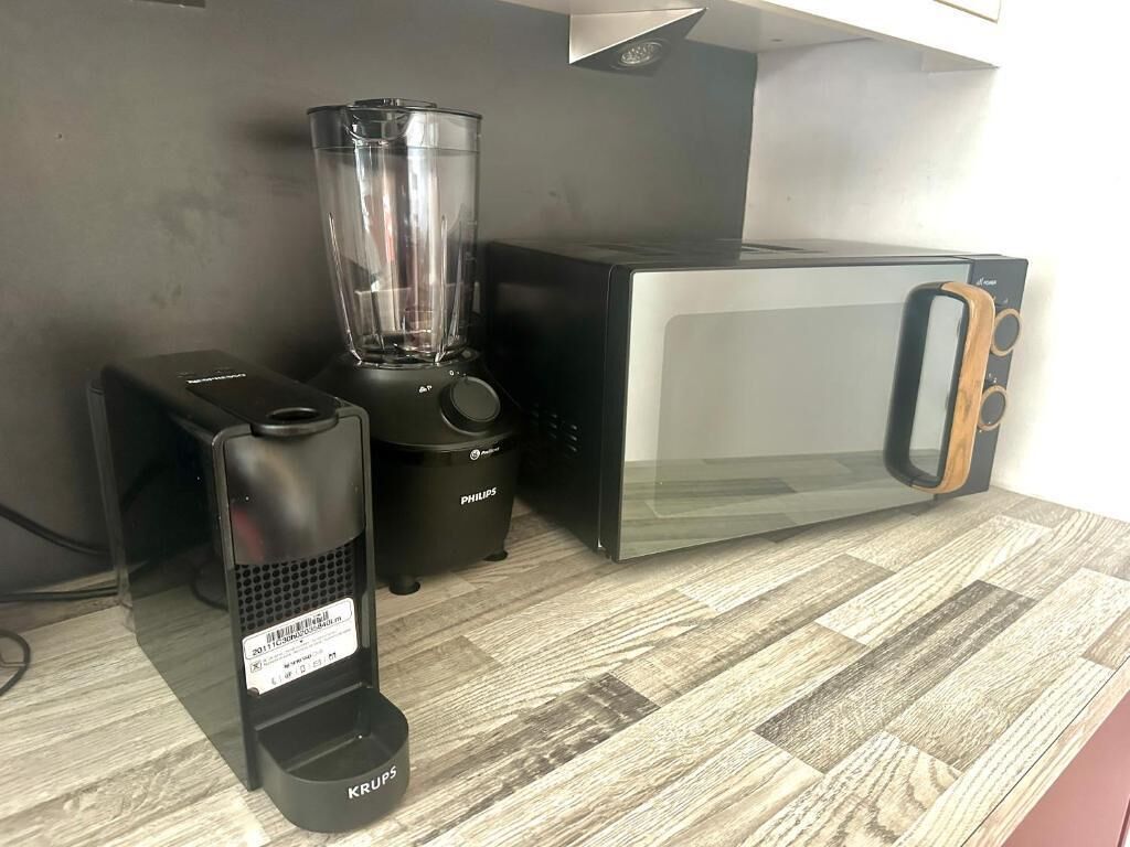 Uma cozinha com liquidificador, micro-ondas e cafeteira em uma bancada de madeira.