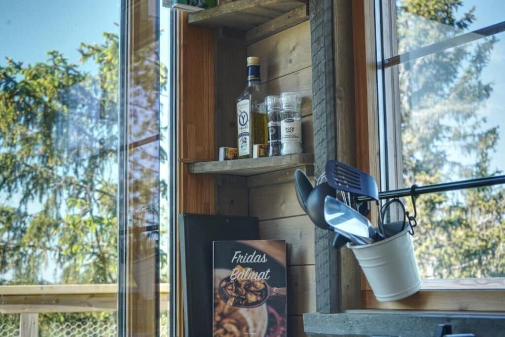 Uma área de cozinha com uma estante de madeira com utensílios e condimentos.