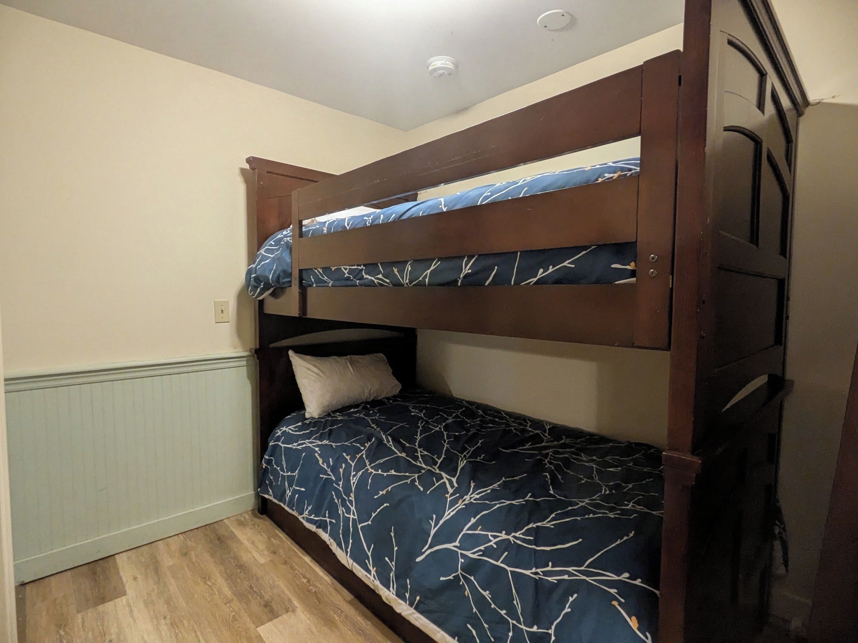 Uma cama beliche com edredom estampado em azul e travesseiro branco.
