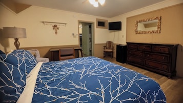 Quarto com cama, cômoda, televisão e uma cadeira.