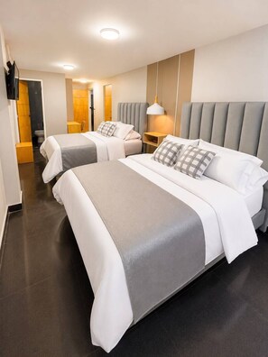 Quarto de hotel com duas camas, televisão, secretária e banheiro.