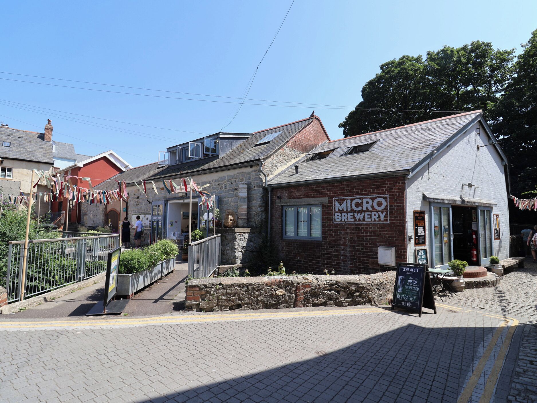 Um edifício de tijolos com uma placa indicando 'MICRO BREWERY' e uma placa de informação para 'LYME REGIS' na frente.
