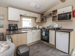 Uma cozinha compacta equipada com micro-ondas, torradeira, chaleira e mini geladeira.