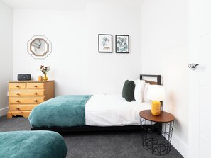 Quarto com cama, penteadeira, espelho e duas quadros na parede.