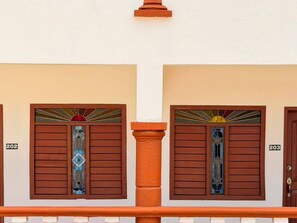 Fachada de edifício com duas portas, cada uma com um número acima, e uma coluna central.