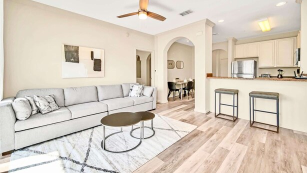 Uma sala de estar moderna com sofá, mesa de centro e ventilador de teto.