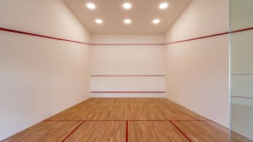 Pista de squash com piso de madeira e linhas demarcatórias vermelhas.