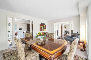 Uma sala de estar espaçosa com uma grande mesa de centro de madeira, sofás estampados e um vibrante arranjo de frutas.