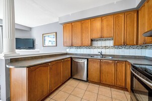 Uma cozinha com armários de madeira, máquina de lavar louça, fogão e painel de azulejos.