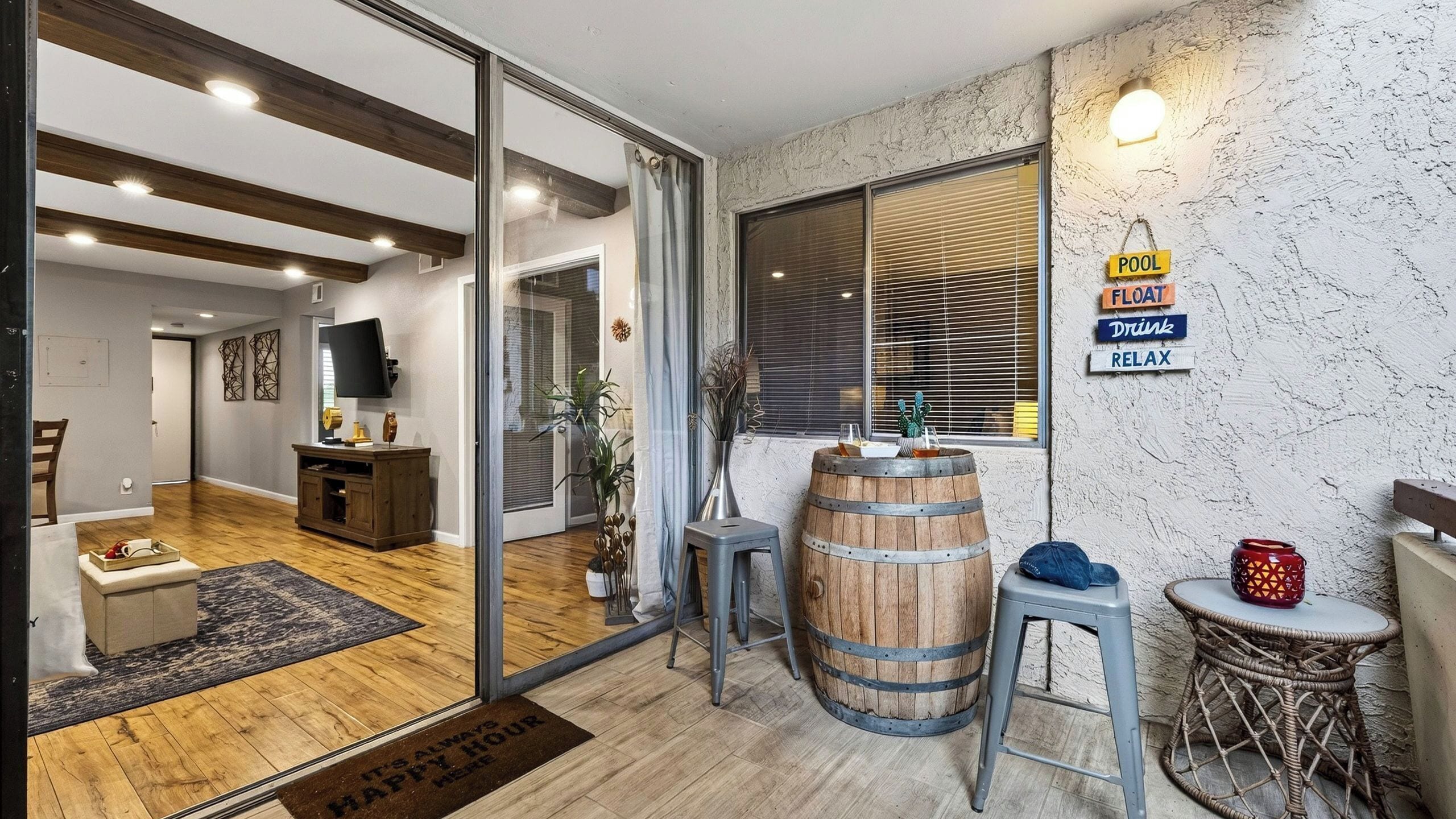 Uma sala de estar moderna com piso de madeira, televisão, armário de madeira e porta de vidro que dá para outro cômodo.