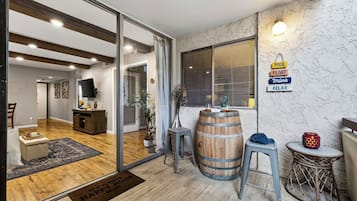 Uma sala de estar moderna com piso de madeira, televisão, armário de madeira e porta de vidro que dá para outro cômodo.