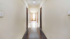Um corredor comprido e estreito com piso polido, que leva até uma porta no final.