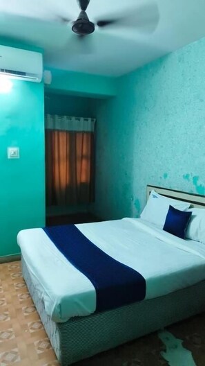 Quarto com cama, ventilador de teto e janela com cortinas.