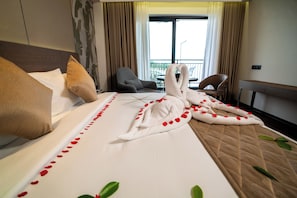 Quarto de hotel com cama, almofadas, uma cadeira e vista para o exterior.