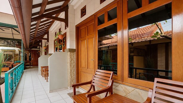 A covered outdoor seating area with wooden benches and a tiled floor.