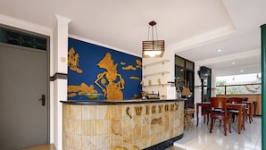 A reception area with a marble counter, a blue wall with golden artwork, and a seating area with wooden chairs.