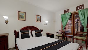 A hotel room with a large bed, two bedside tables, a chair, and a window with curtains.