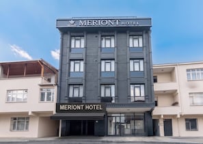 Um edifício de hotel com vários andares e uma placa visível com a inscrição 'MERIANT HOTEL'.
