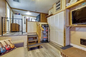 Um espaço de estar compacto com cozinha compacta, televisão na parede e escada para um andar superior.