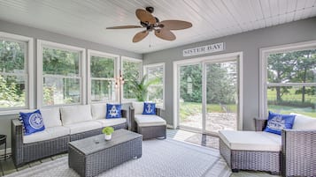 Uma sala de estar com janelas amplas, ventilador de teto e uma placa com a inscrição 'SISTER BAY'.